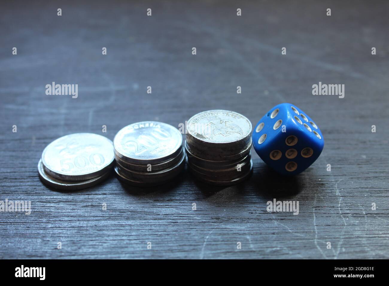 Coins and dice with wooden background Stock Photo - Alamy