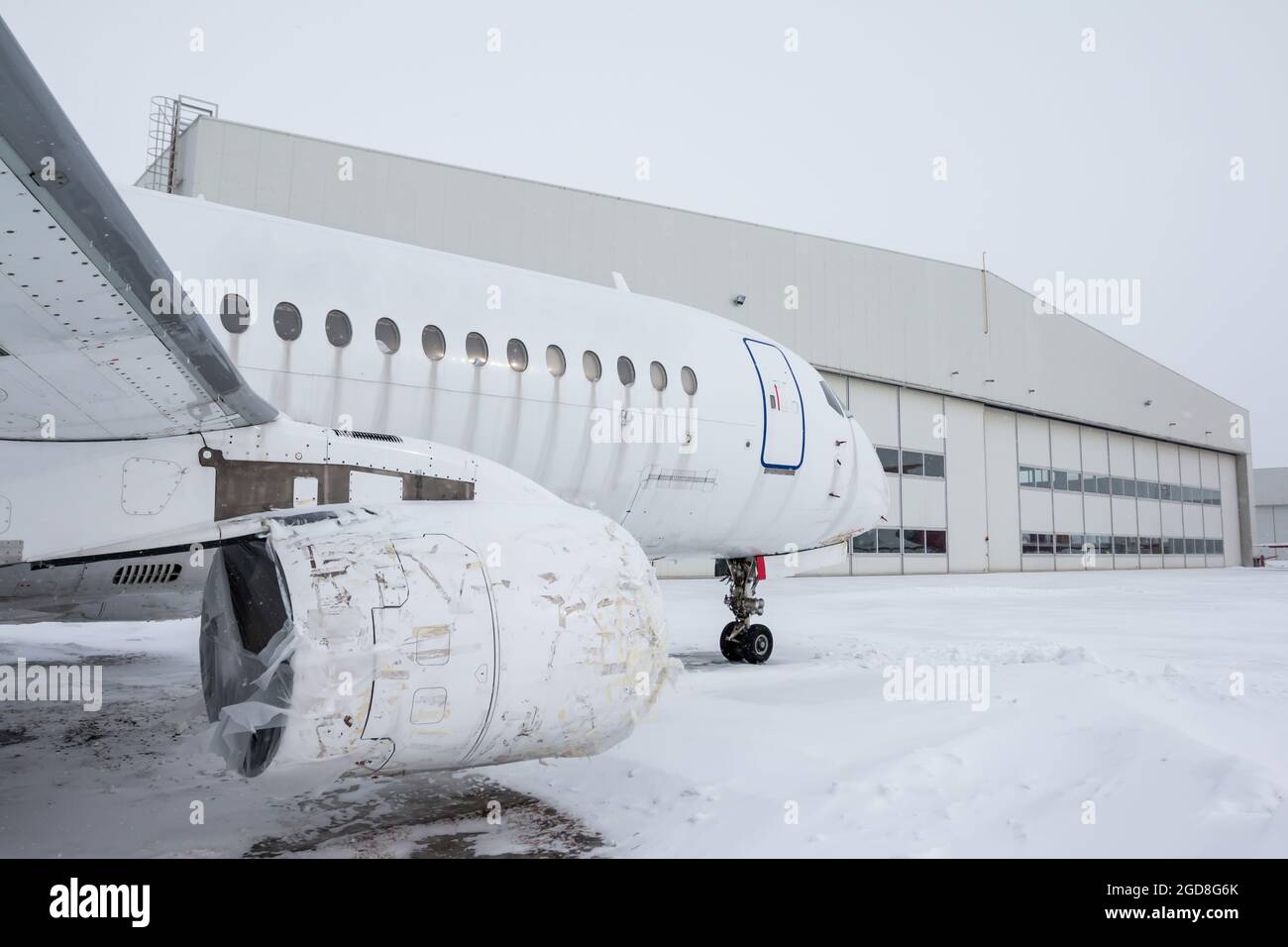 White passenger airplane near the aircraft hangar in cold winter ...
