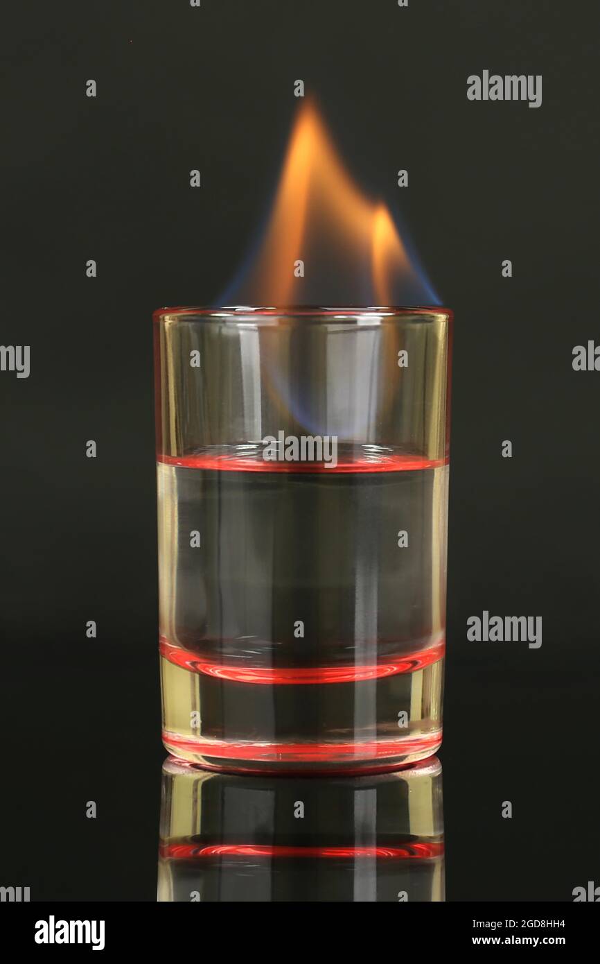 Glass with burning alcohol on black background Stock Photo - Alamy