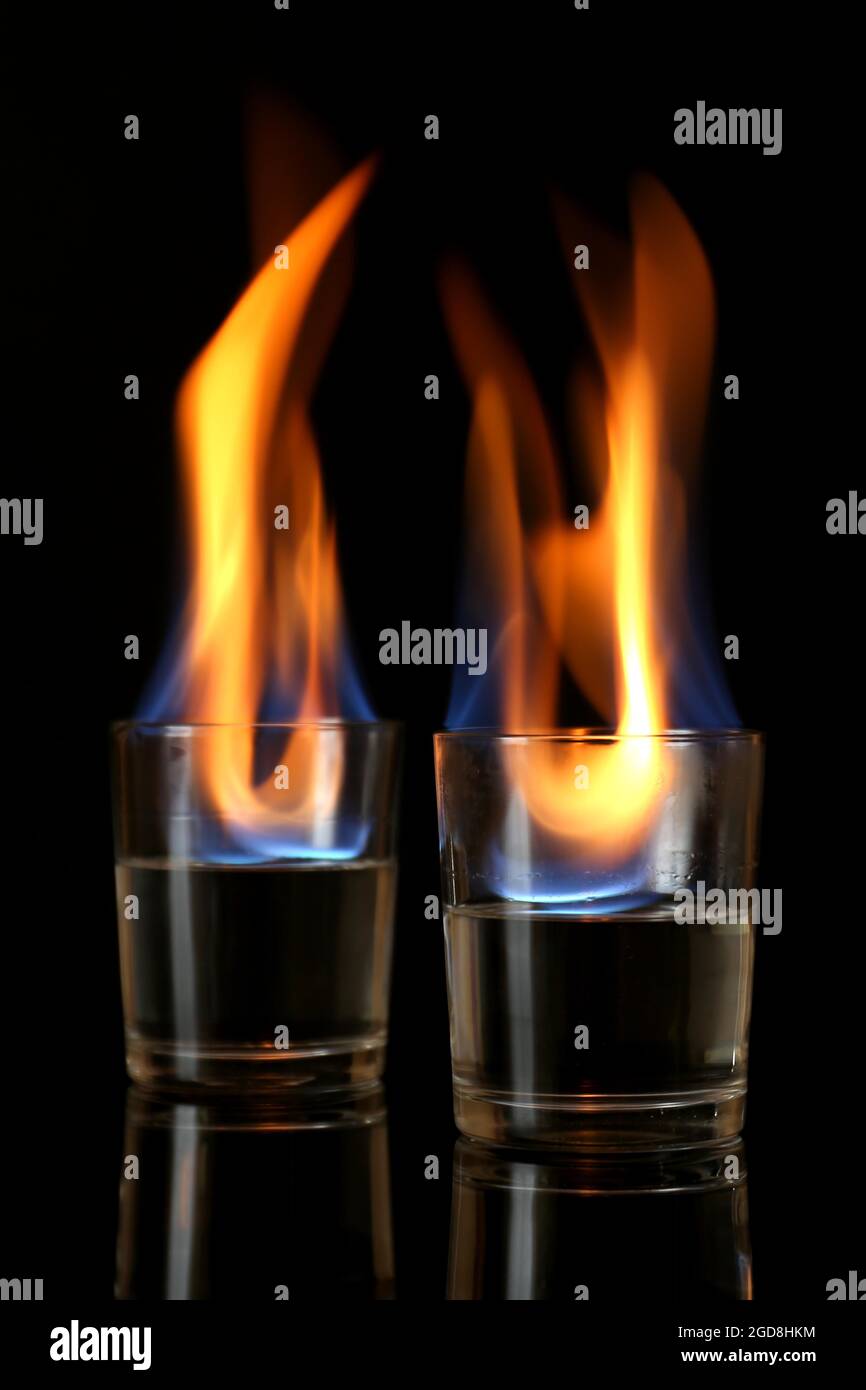 Glasses with burning alcohol on black background Stock Photo - Alamy