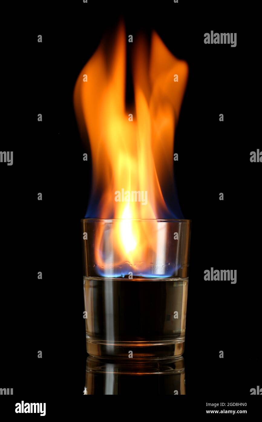 Glass with burning alcohol on black background Stock Photo - Alamy
