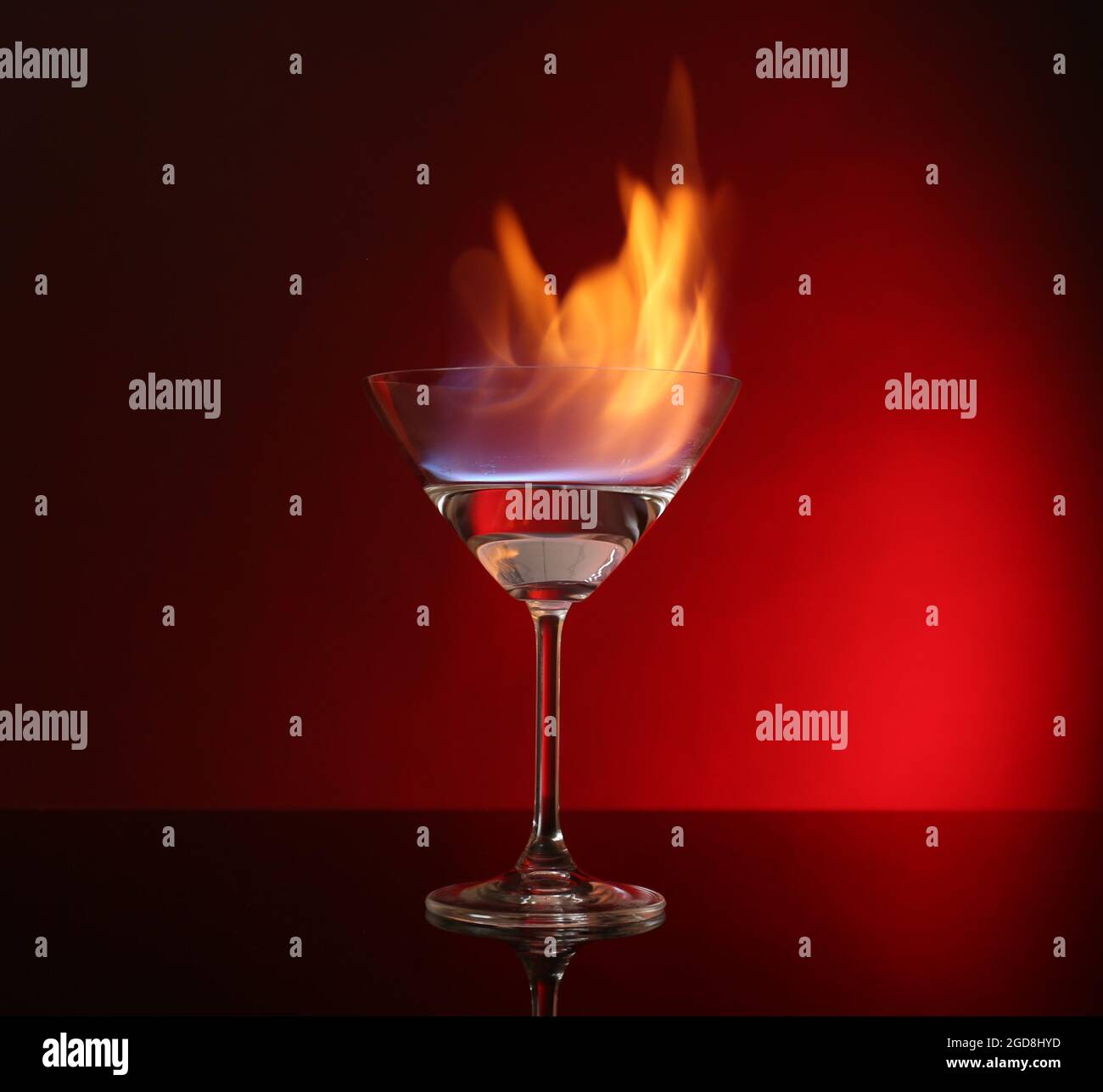 Glass with burning alcohol on red background Stock Photo - Alamy
