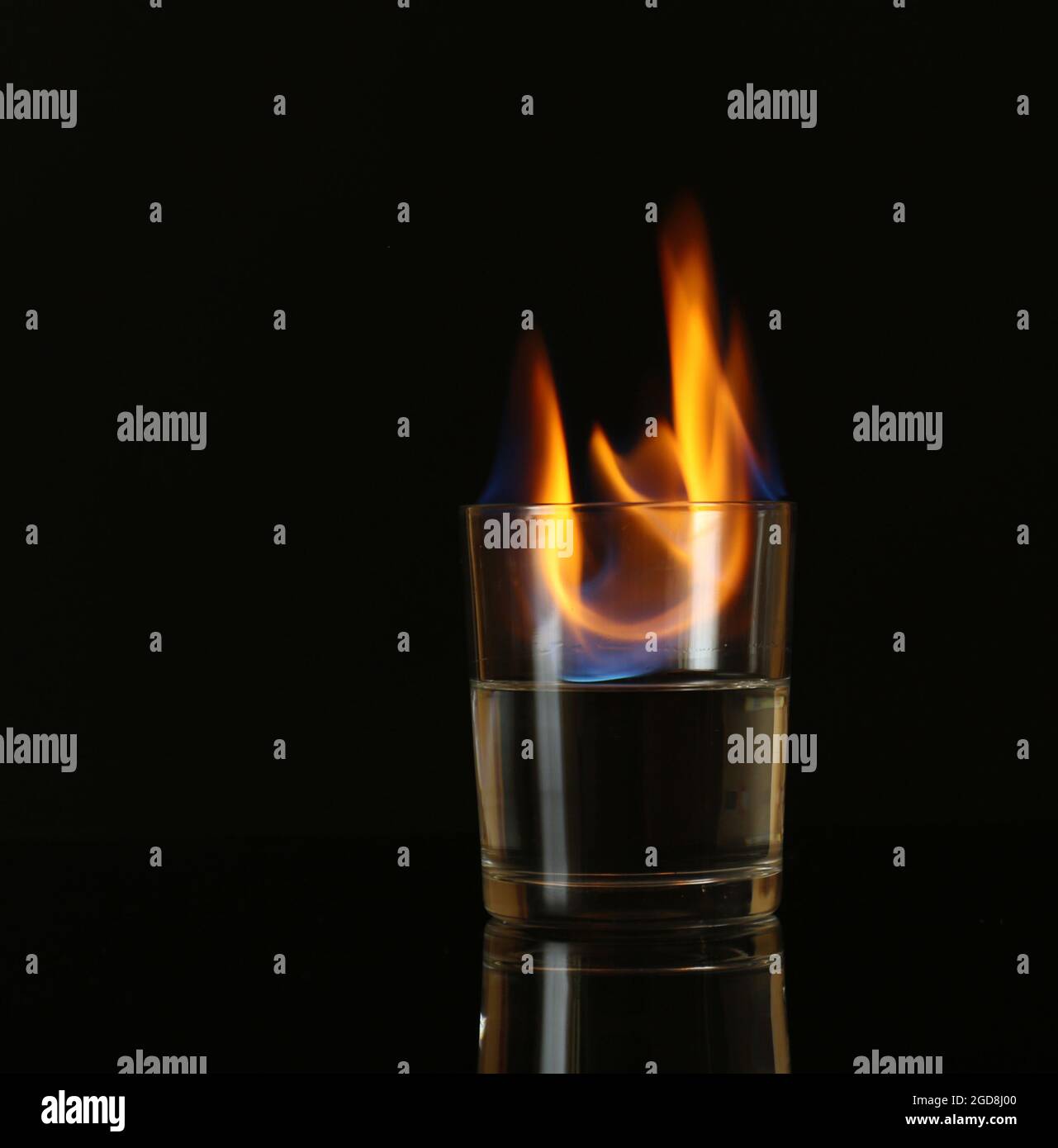 Glass with burning alcohol on black background Stock Photo - Alamy