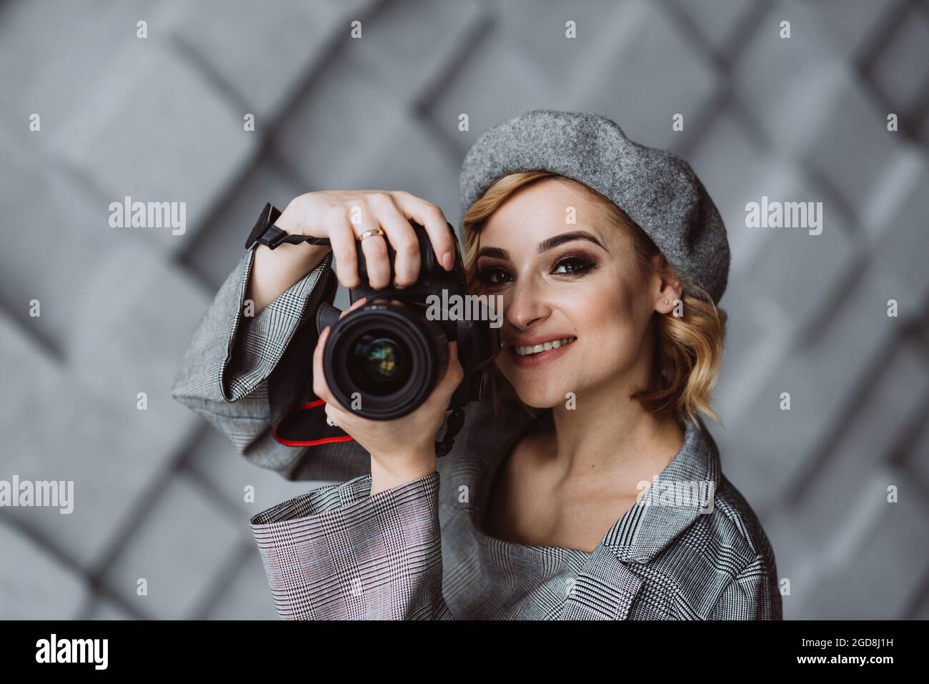 Portrait of a beautiful stylish woman photographer in a gray outfit ...