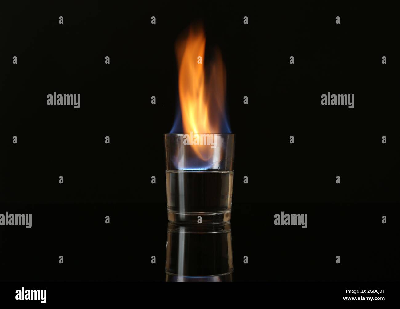 Glass with burning alcohol on black background Stock Photo - Alamy