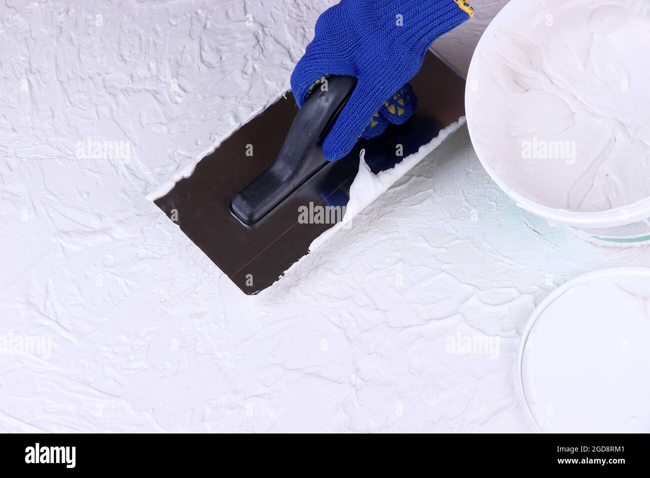 Construction trowel and worker hands on wall with textured plaster ...
