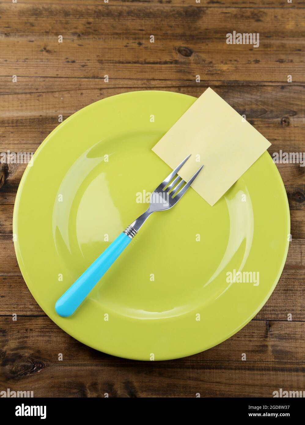 Empty note paper attached to fork, on plate, on color wooden background ...