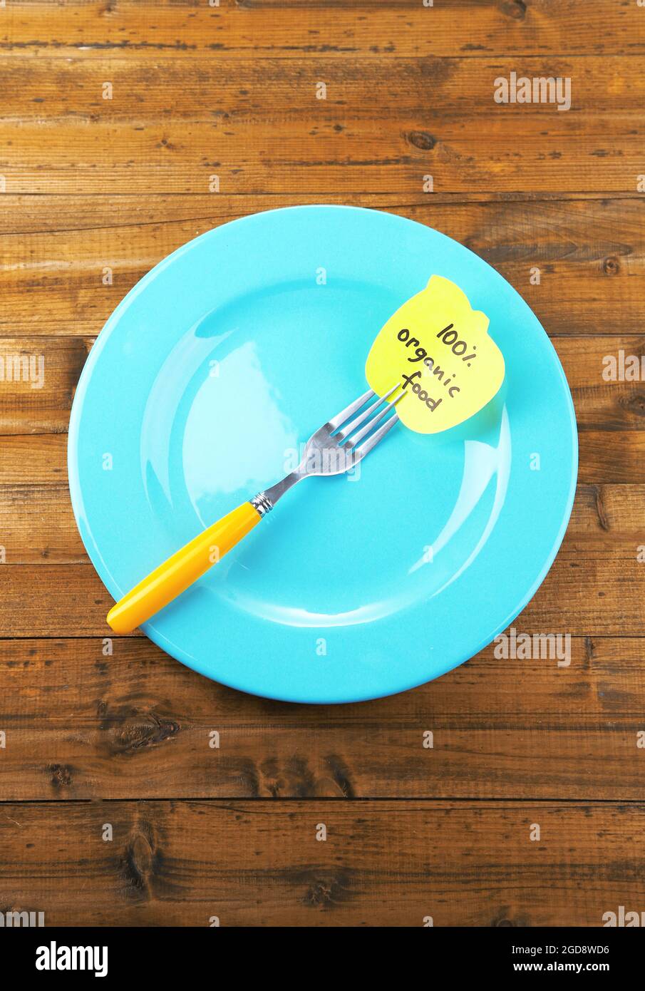 Note paper with message attached to fork, on plate, on color wooden ...