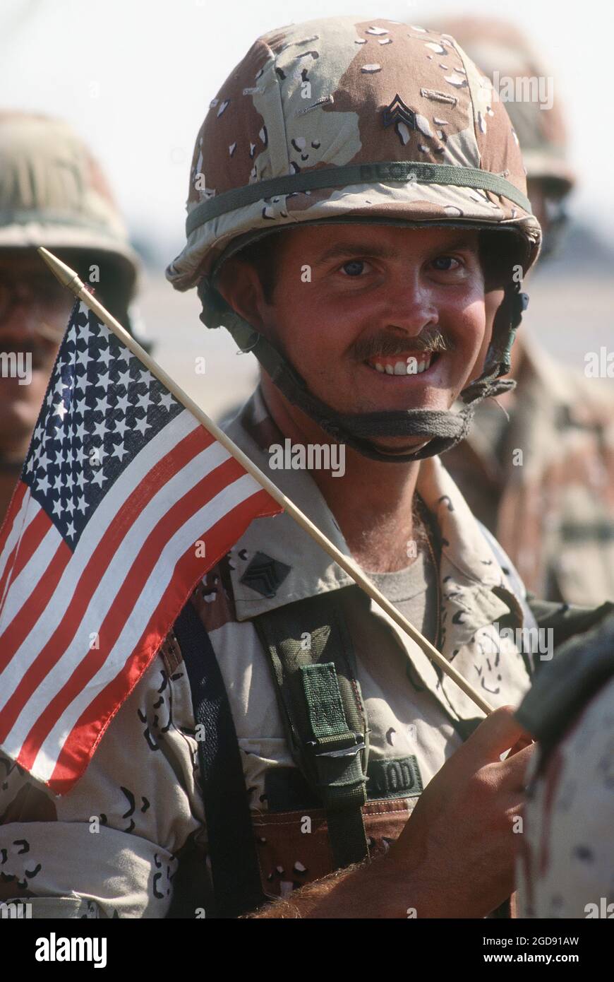A member of the 101st Airborne Division holds up a miniature U.S. Flag ...
