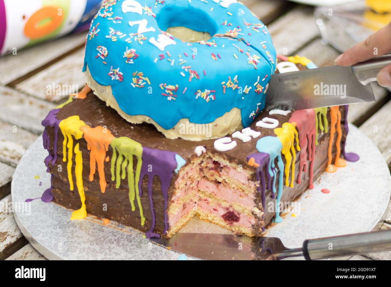 A creative two-layer cake featuring a colorful donut-shaped top and a ...