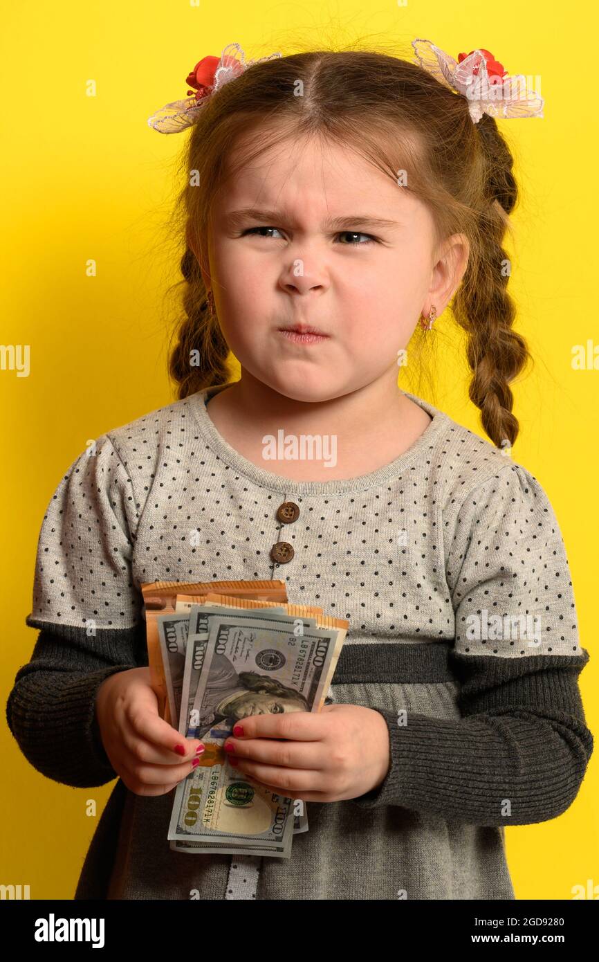 Cute little girl on a yellow background background holds the world's ...