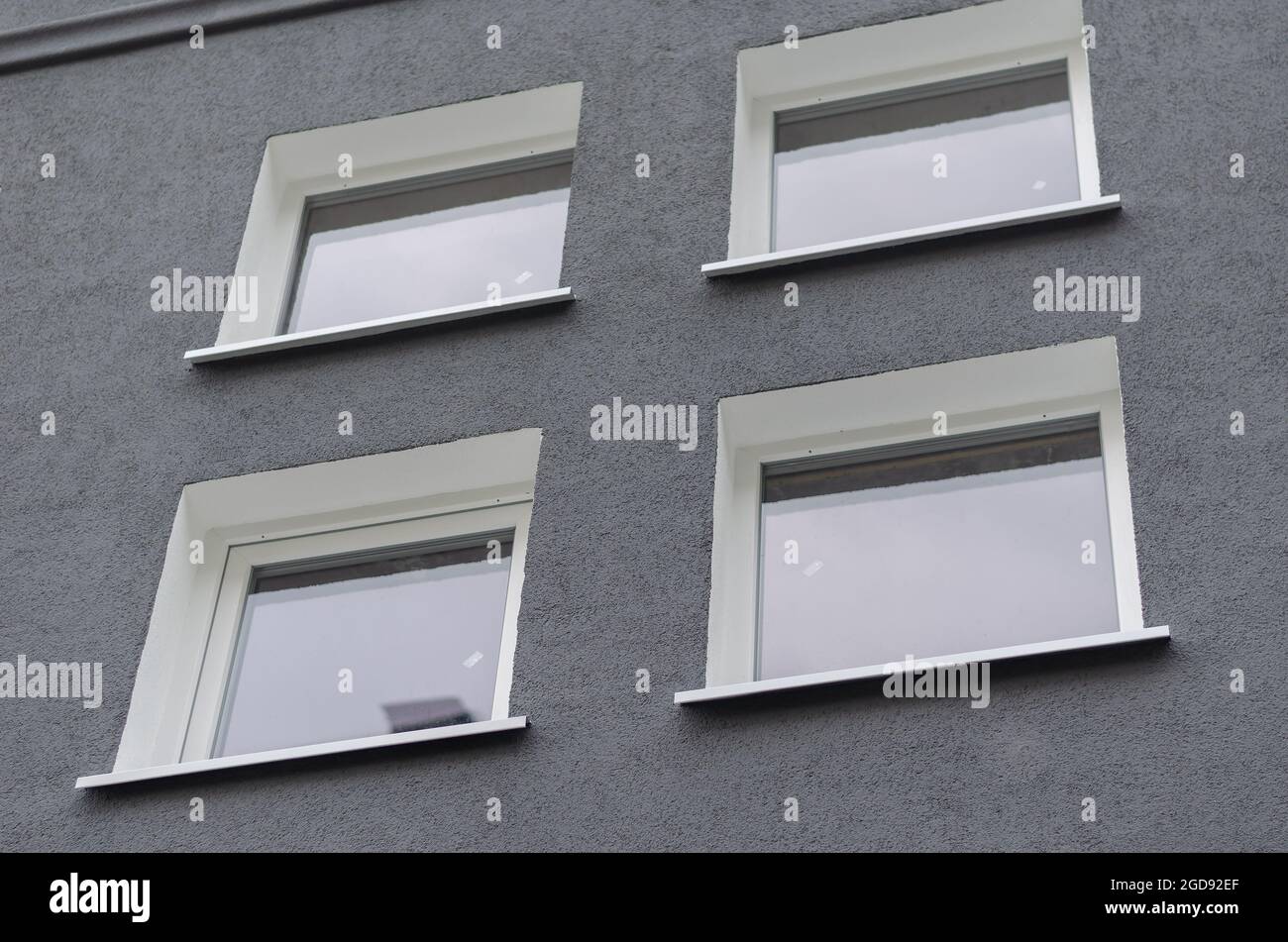 Dark gray exterior wall with white windows. Four square windows on the ...