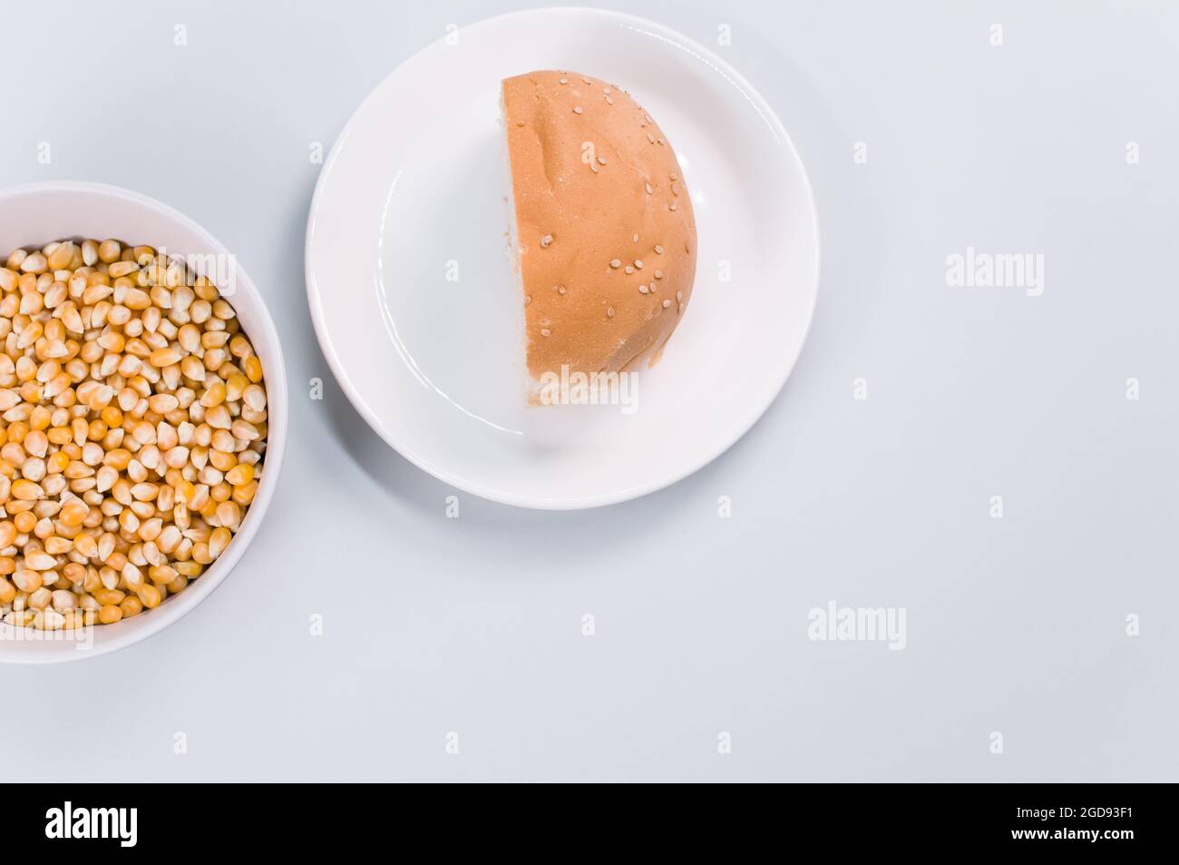 Top view of half bread bun and corn grains on a plate isolated on white ...
