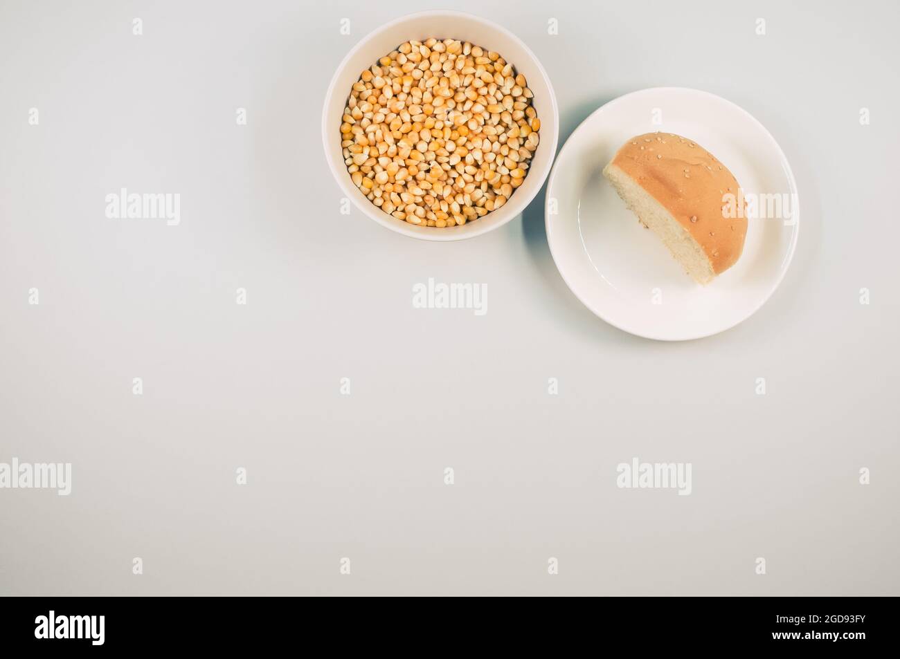 Top view of half bread bun and corn grains on a plate isolated on white ...