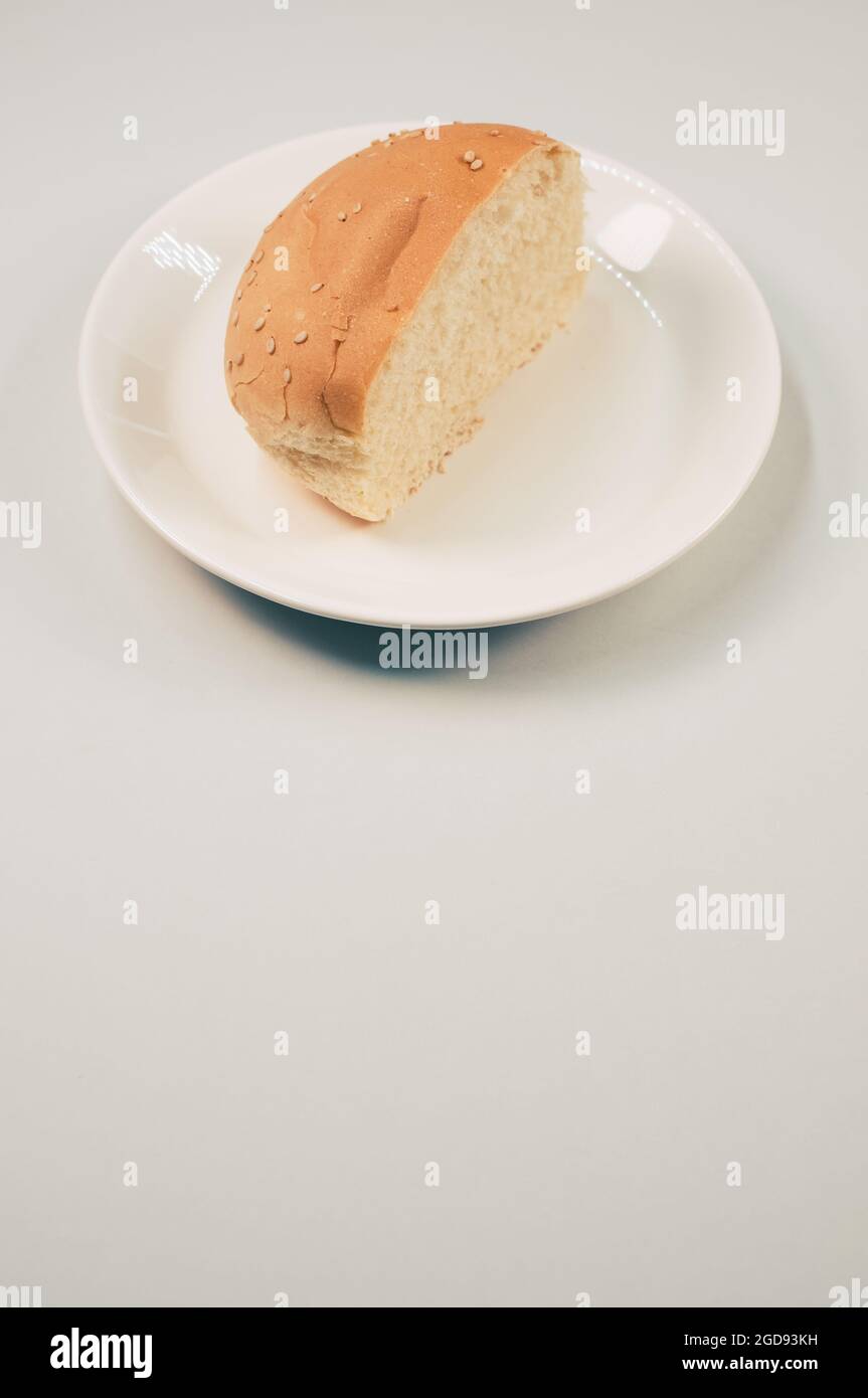 Vertical shot of half bread bun on a plate isolated on white background ...