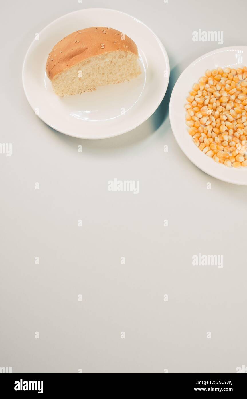 Vertical shot of half bread bun and corn grains on a plate isolated on ...