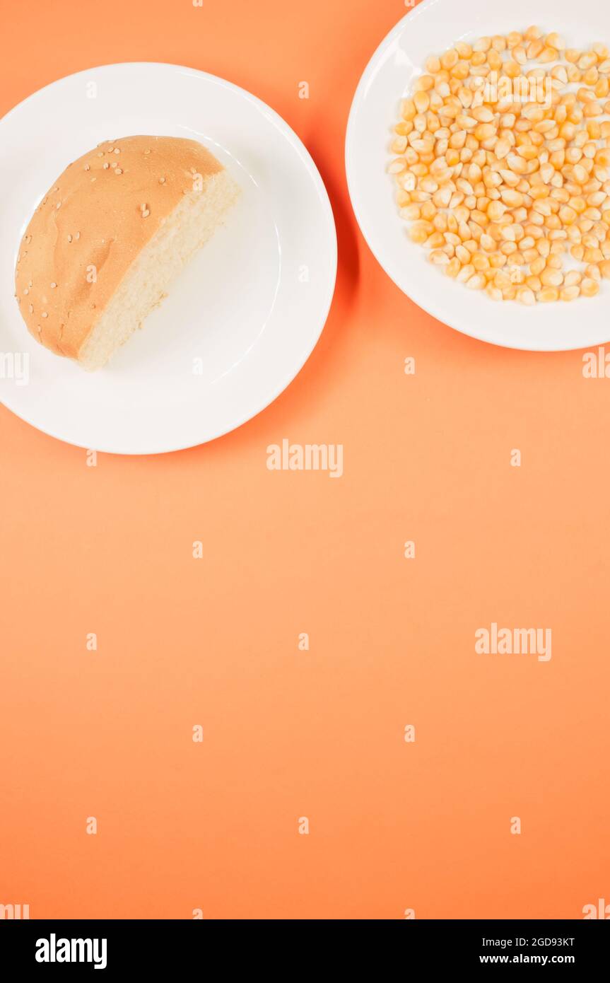 Vertical shot of half bread bun and corn grains on a plate isolated on ...