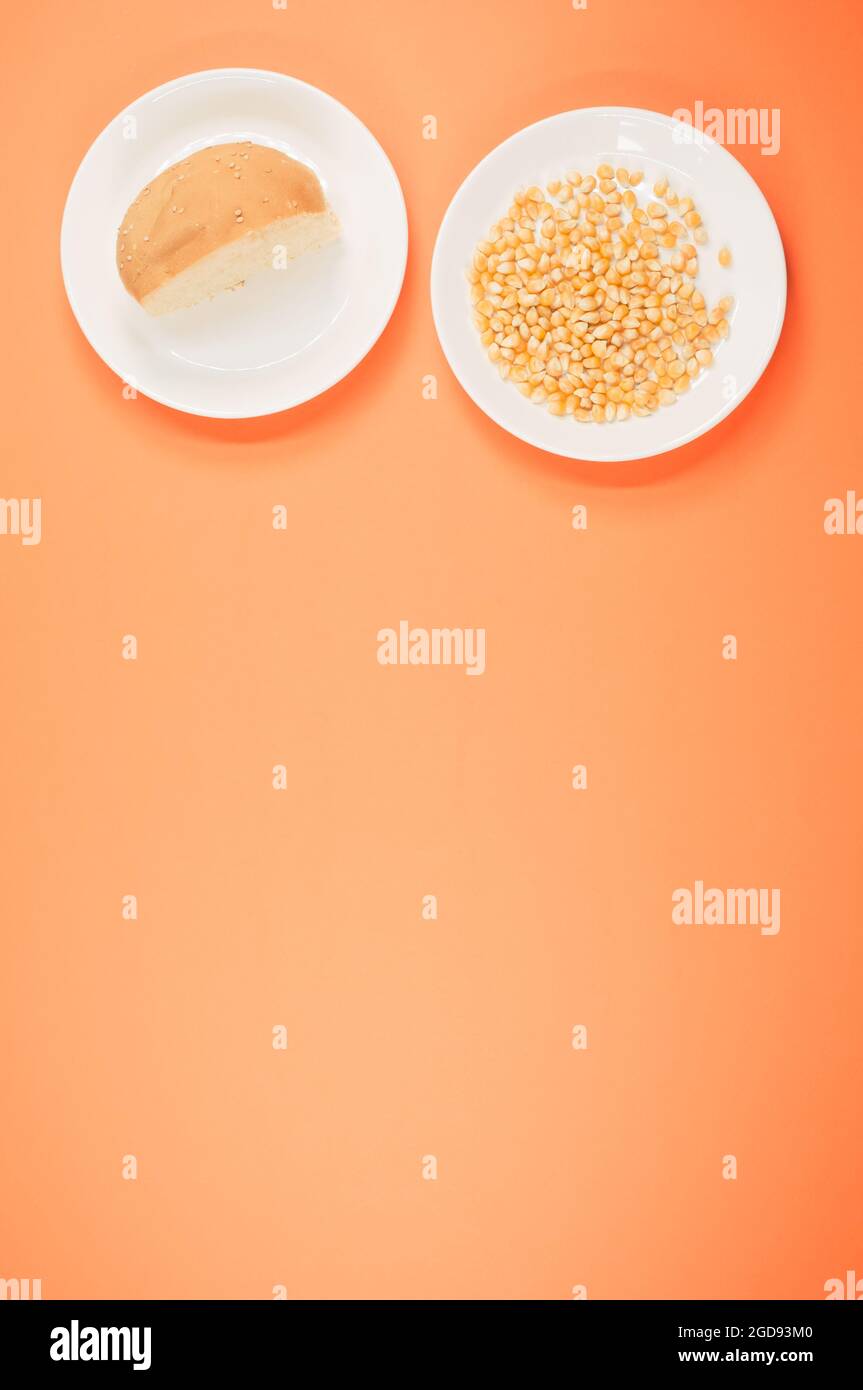 Vertical shot of half bread bun and corn grains on a plate isolated on ...