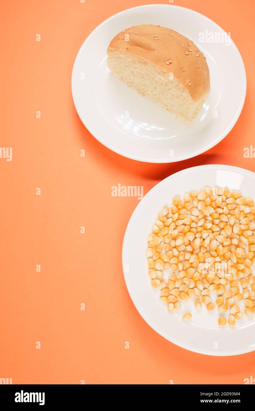 Vertical shot of half bread bun and corn grains on a plate isolated on ...