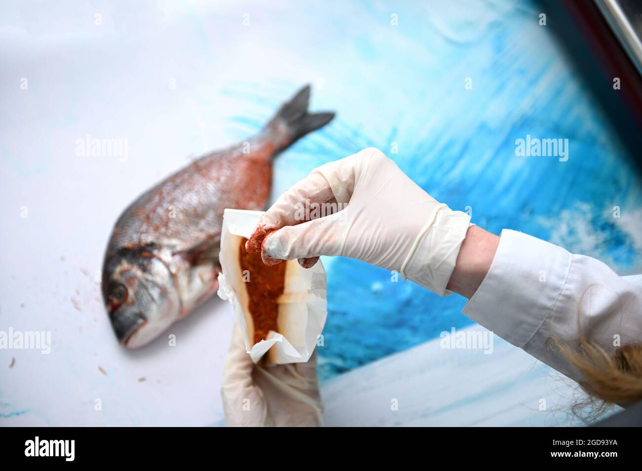 Focus on the chef's gloved hands. The fishmonger holds a paper bag of ...