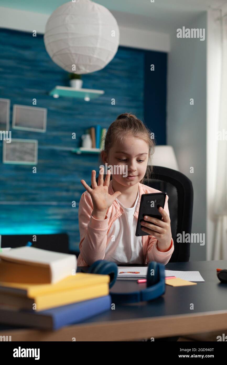 Little student girl using video call on smartphone to join online class ...
