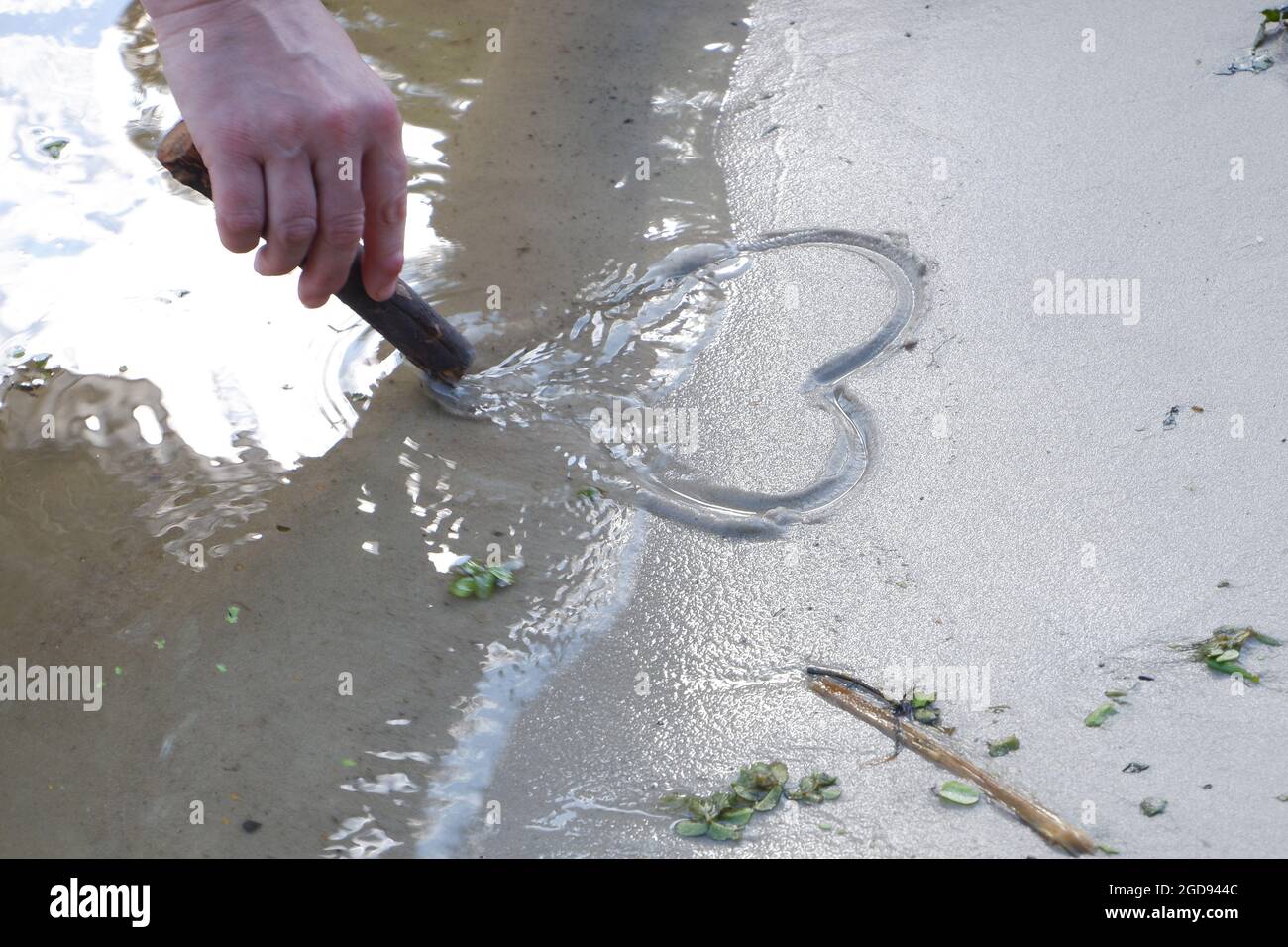 On the sand, the image of the heart is washed away by the rolling wave ...