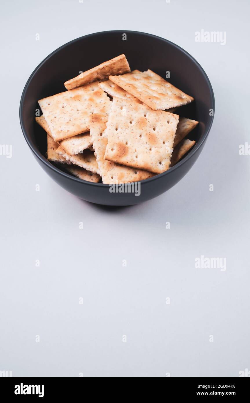 Vertical shot of square crackers on a bowl isolated on white background ...