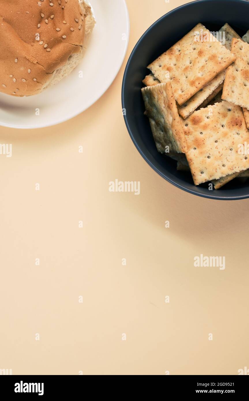 Vertical shot of square crackers and bread bun isolated on light brown ...