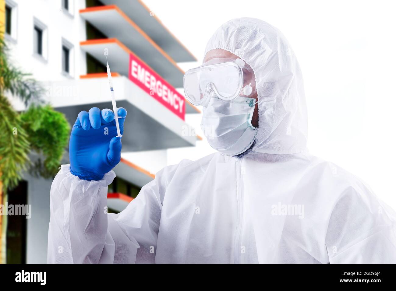 Health worker man with a protective suit and gloves holding syringe on ...
