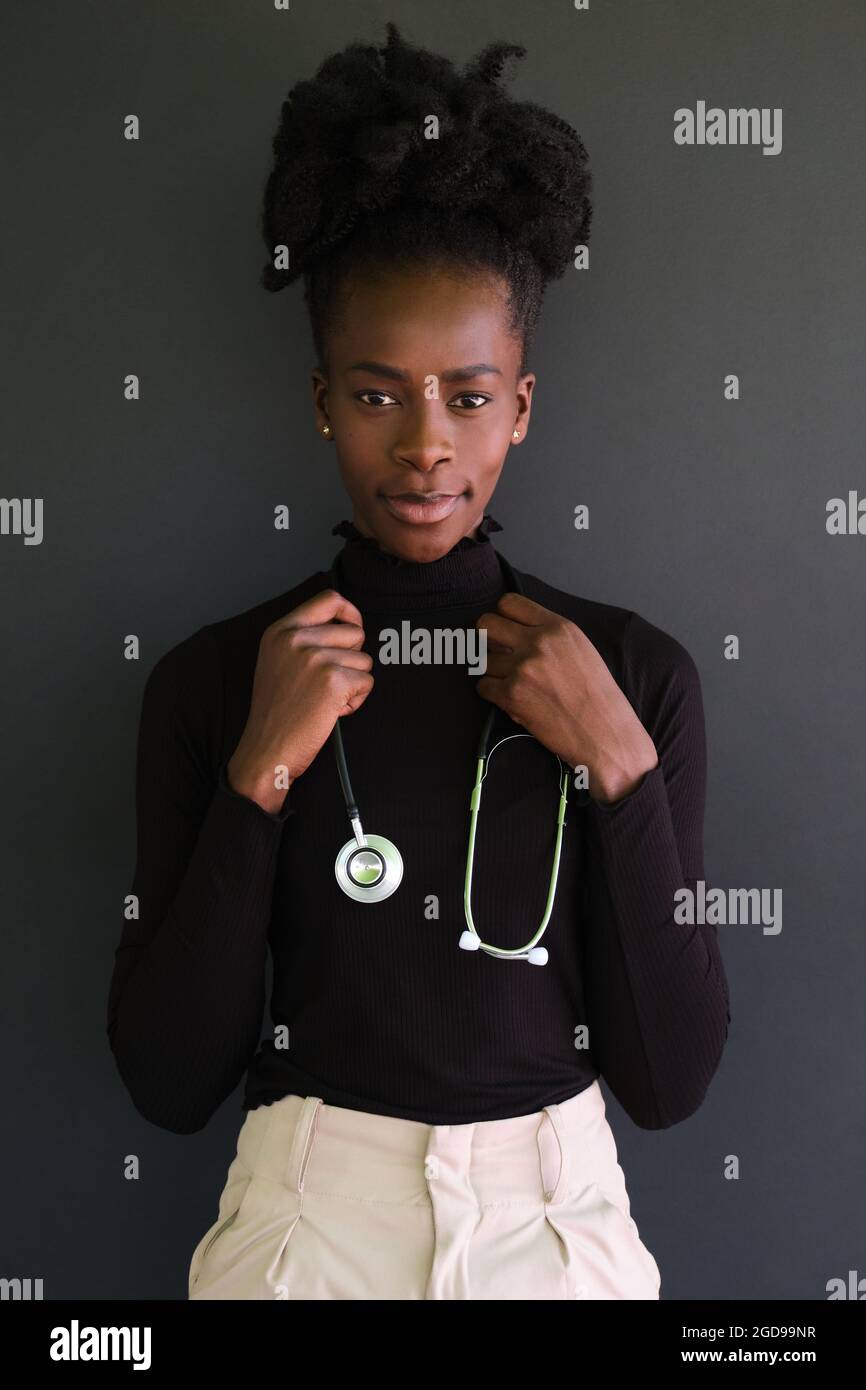 Young female african doctor with stethoscope in a black background ...