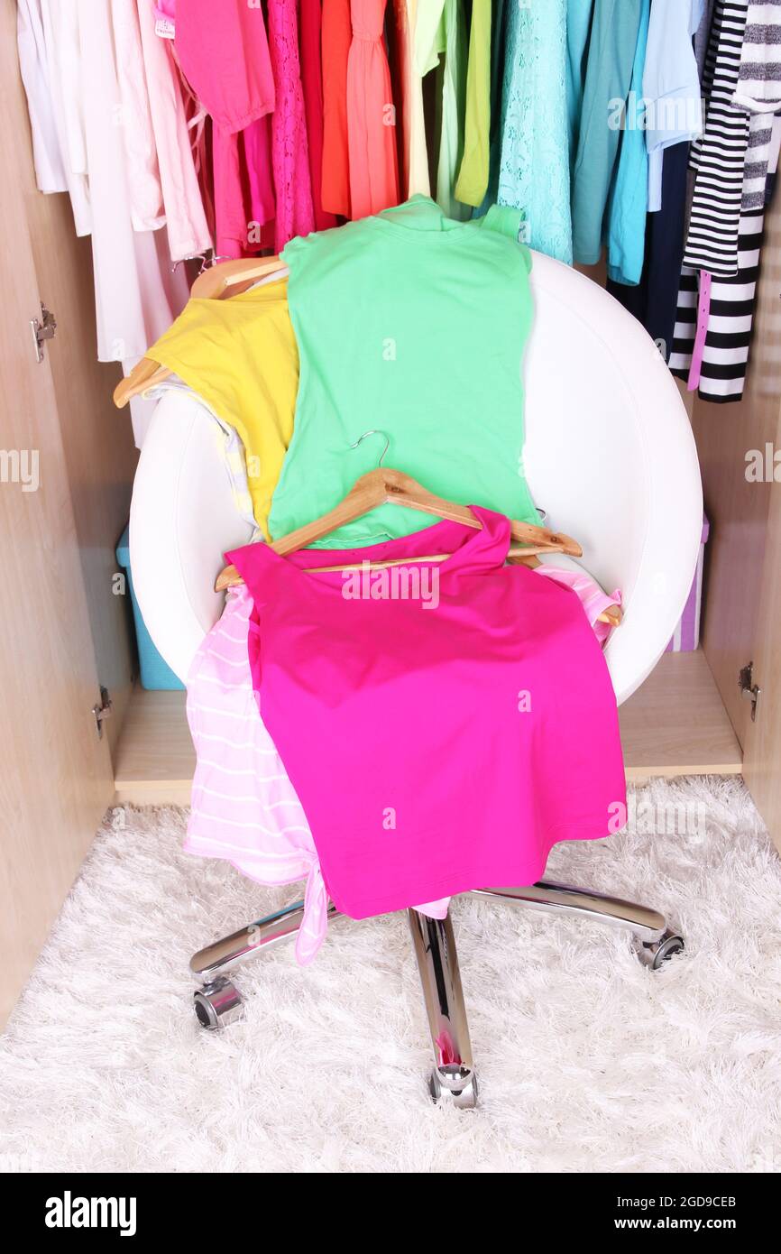 Female clothes in wardrobe and chair in room Stock Photo - Alamy