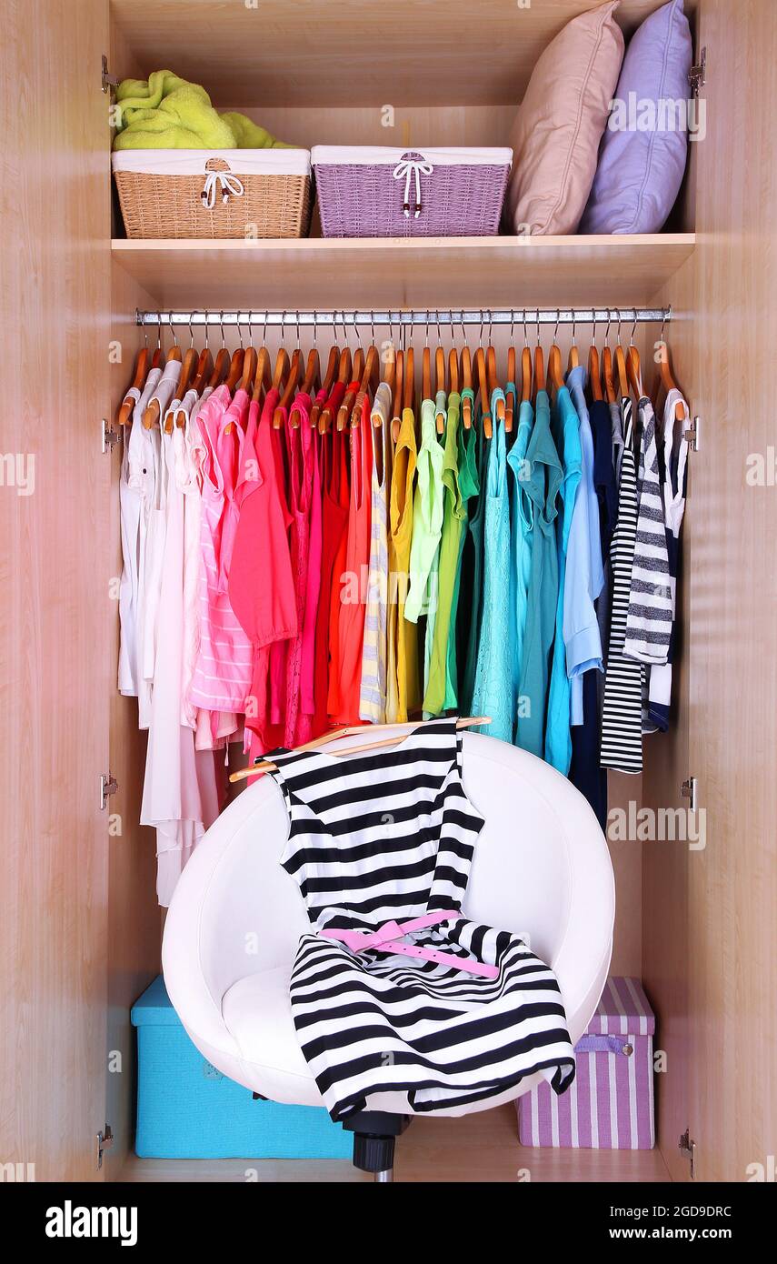 Female clothes in wardrobe and chair in room Stock Photo - Alamy