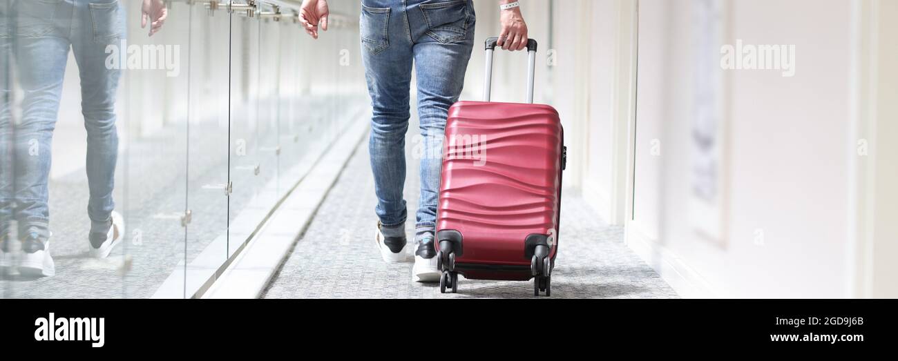 Rear view of man pulling suitcase down hotel corridor Stock Photo - Alamy