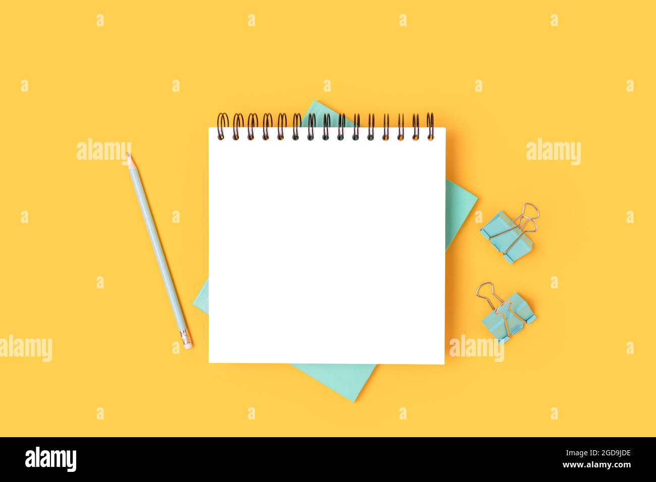 Workspace with square notepad mockup and stationery on a yellow ...