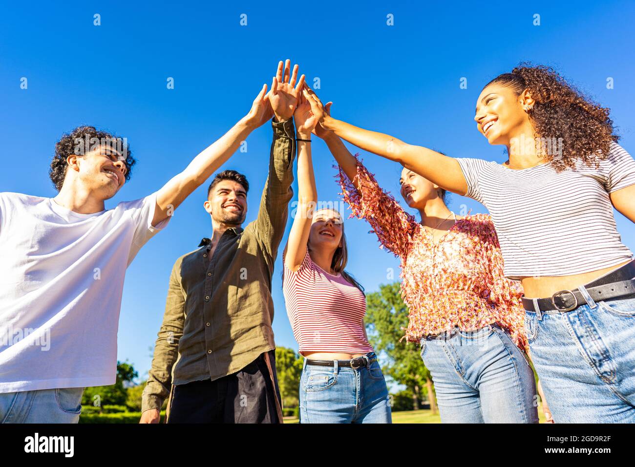Group of happy gen z friends touching hand raised up to each other ...