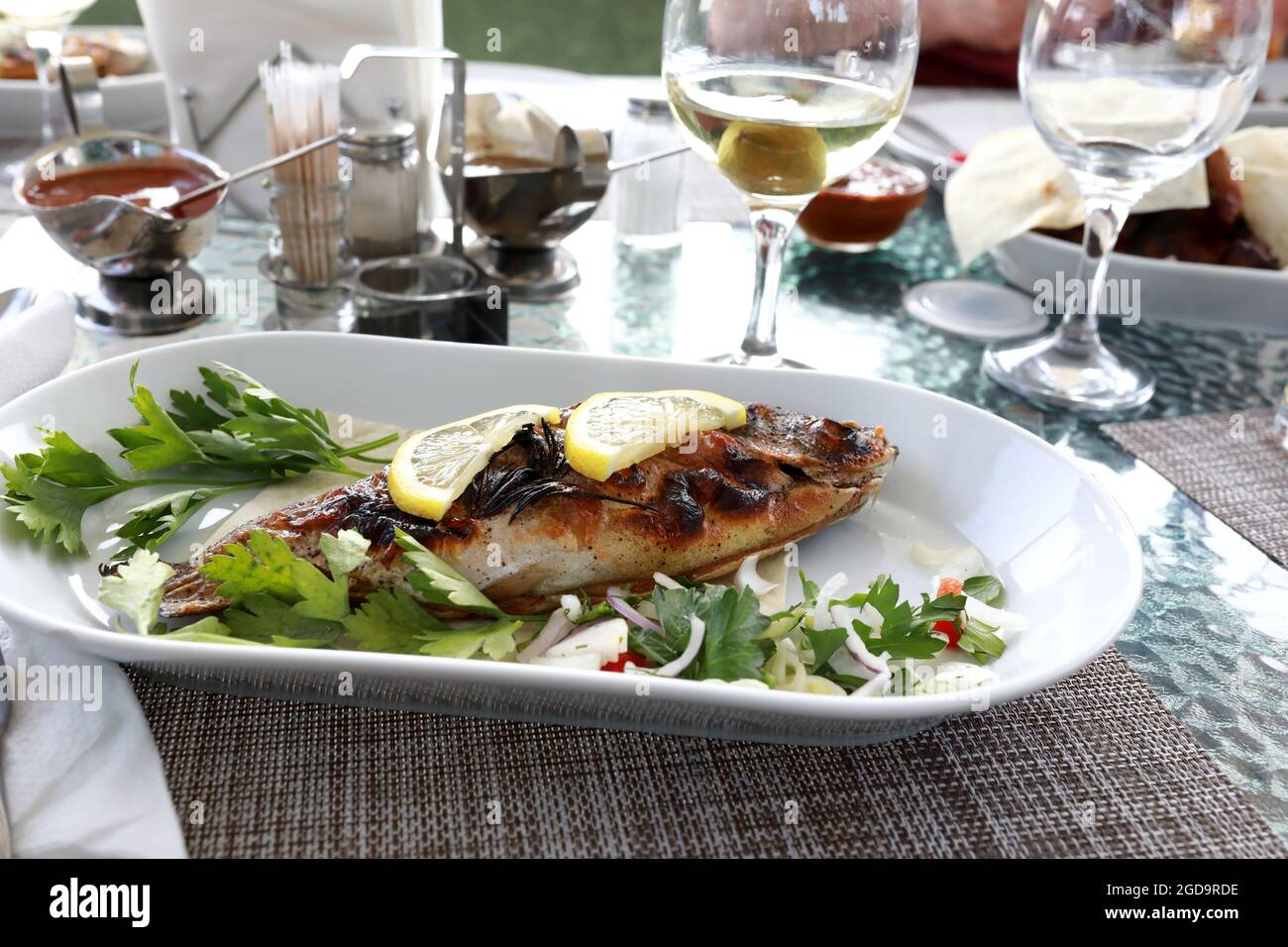 Fried trout with herbs on plate in restaurant Stock Photo - Alamy