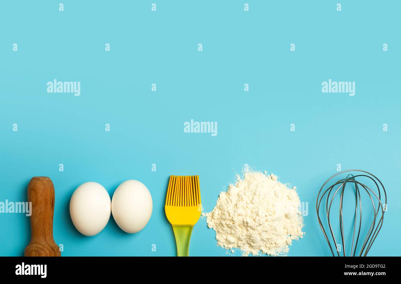 Baking and dough background. Wheat flour and kitchen items on a blue ...