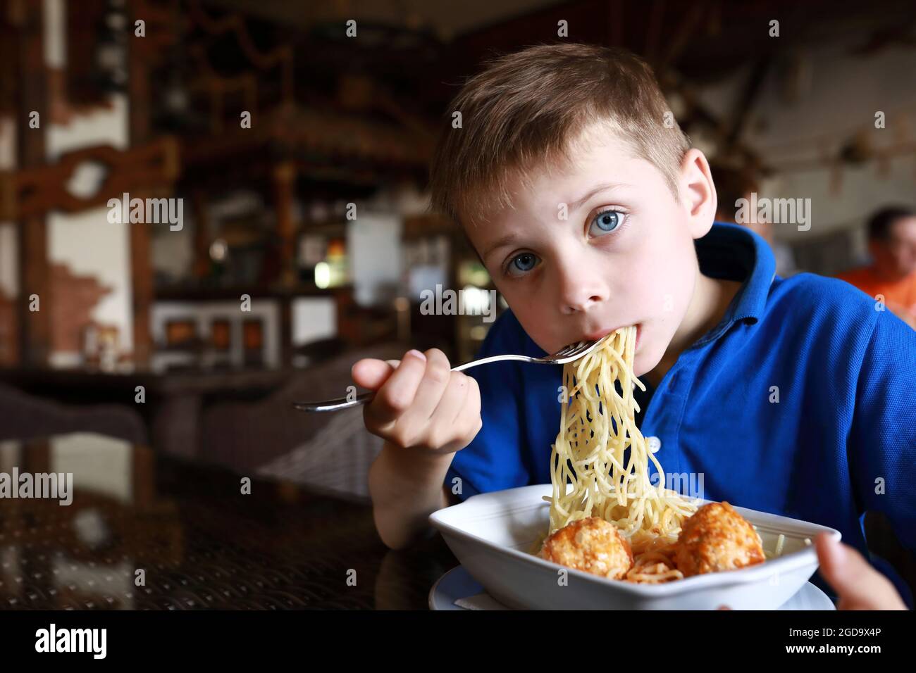 Boy eating meatballs in tomato sauce with spaghetti in restaurant Stock ...