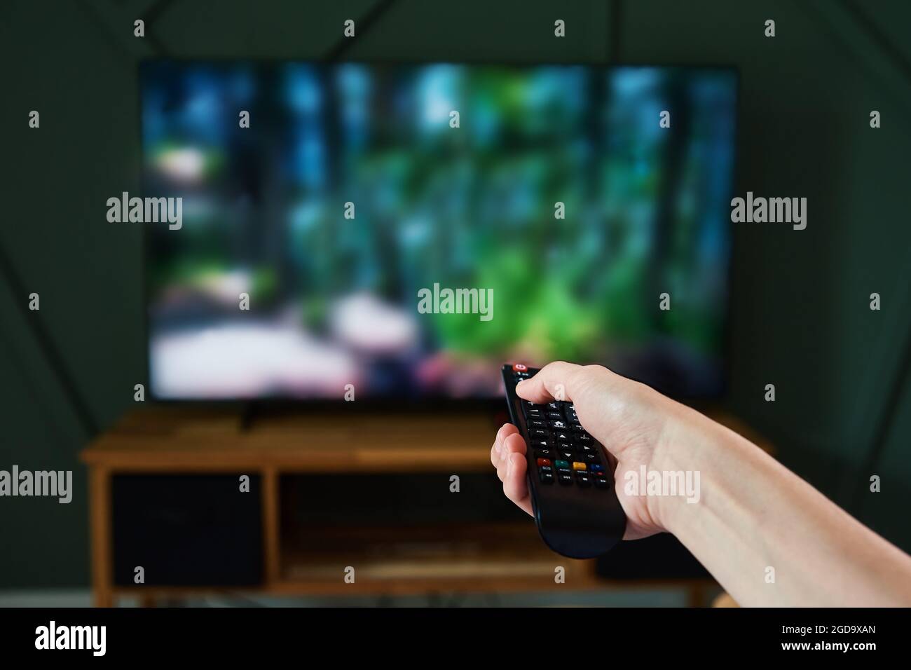 Woman resting at home. Person watch TV set on the sofa and switch ...