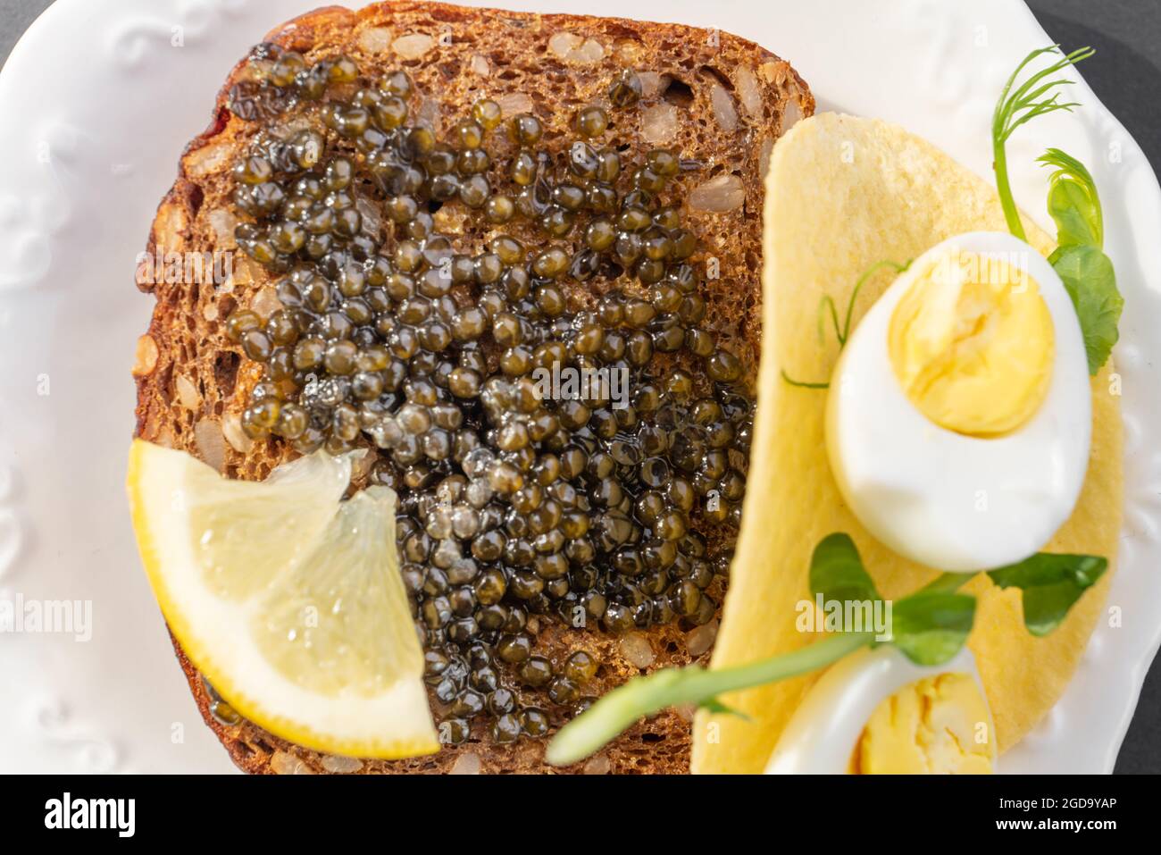 Black caviar on a festive sandwich with eggs, lemon, greenery. Healthy ...