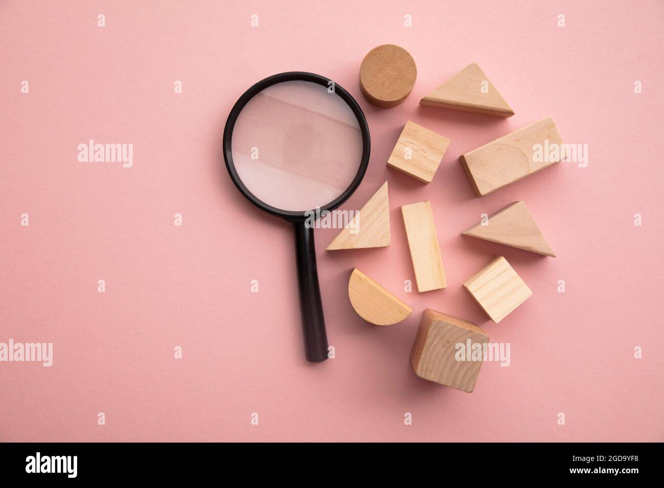 Magnifying glass with a selection of different shaped wooden blocks ...