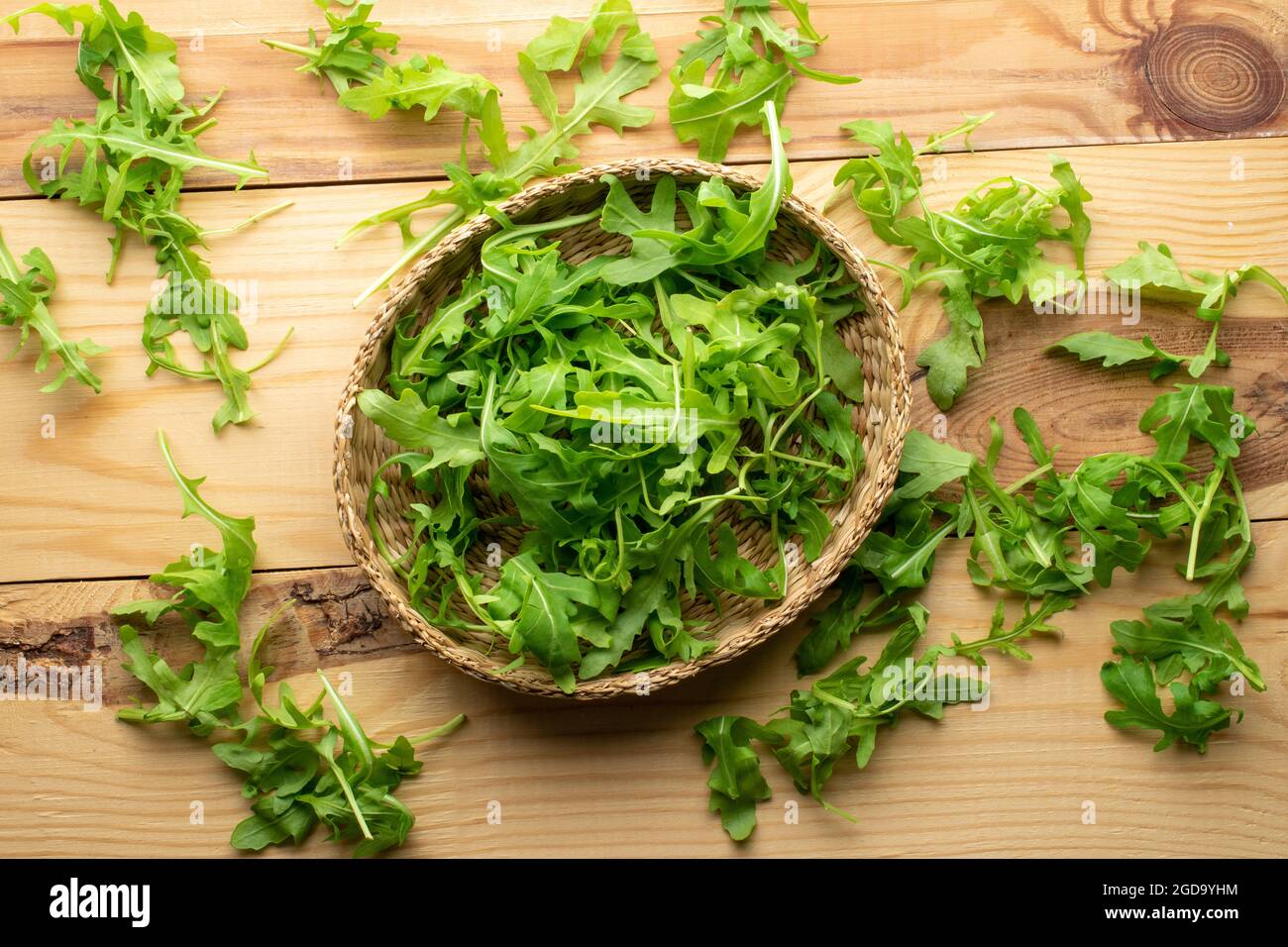 Fresh green arugula in a plate, close-up, on a wooden table, top view ...