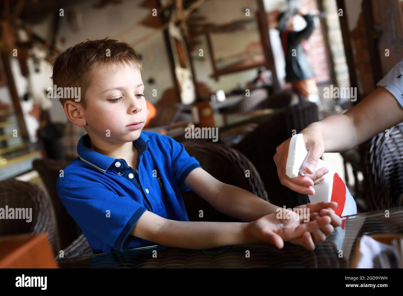 Person sprinkles antiseptic on hands of child in restaurant Stock Photo ...