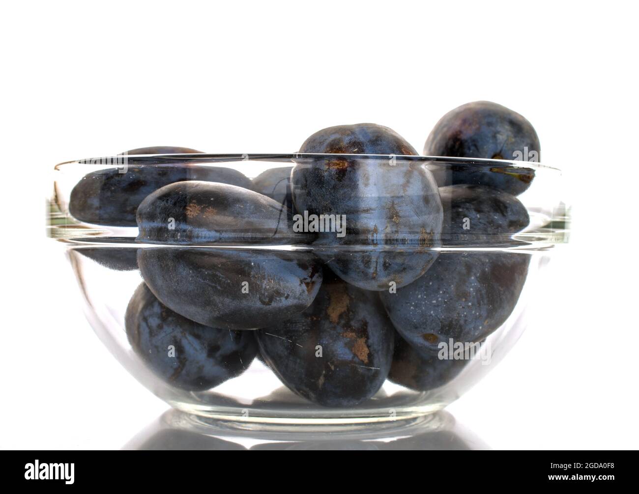 Several ripe organic Damson plums in a glass bowl, close-up, isolated ...