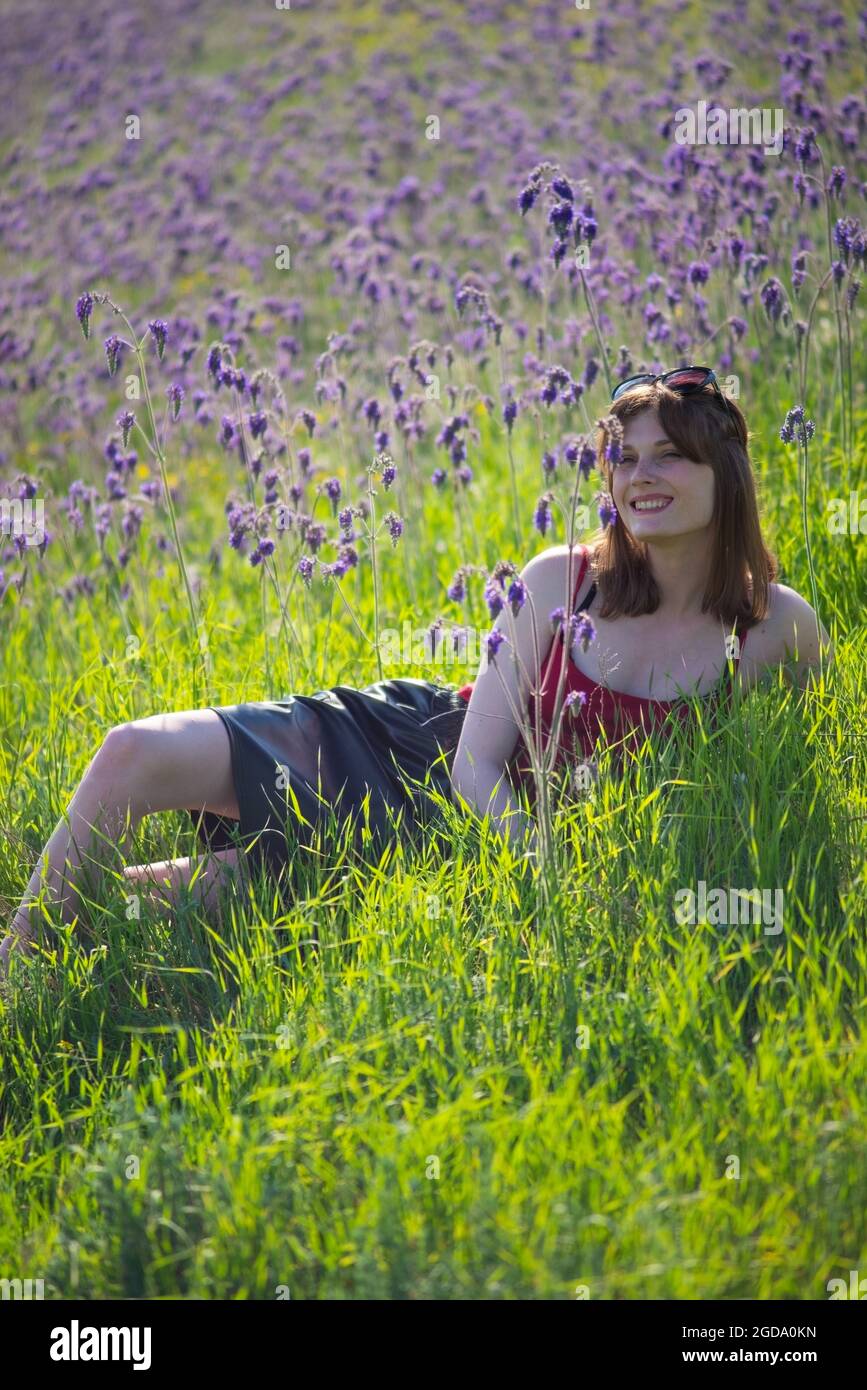 portrait of a fashionable beautiful young girl lying in a flower field ...