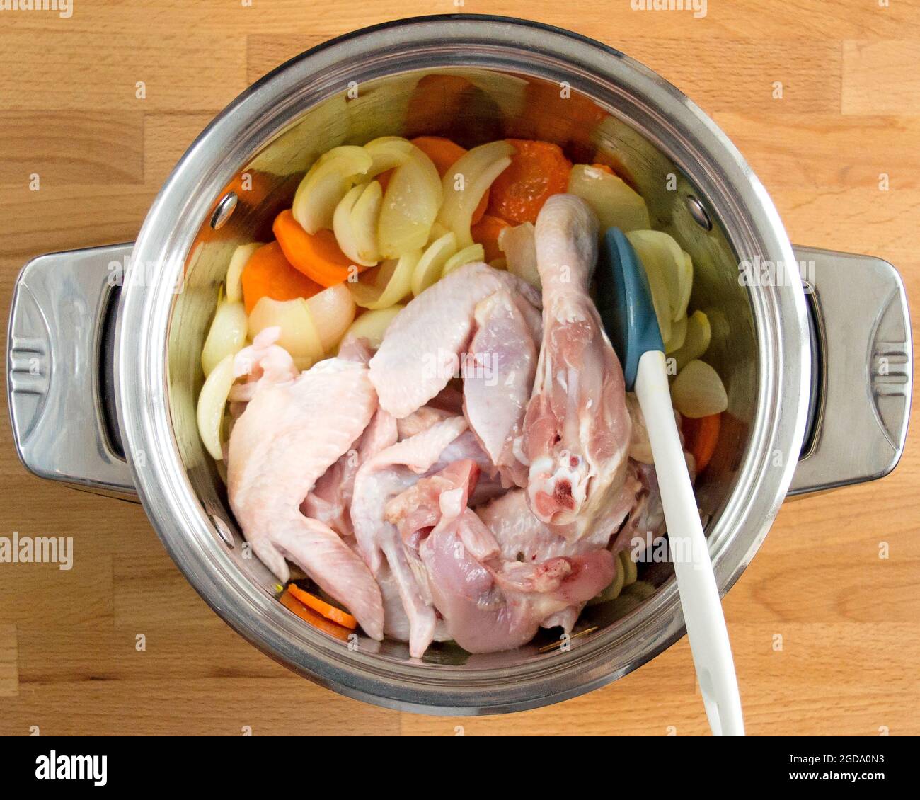 Vegetables and raw chicken in a saucepan. Preparation for cooking broth ...