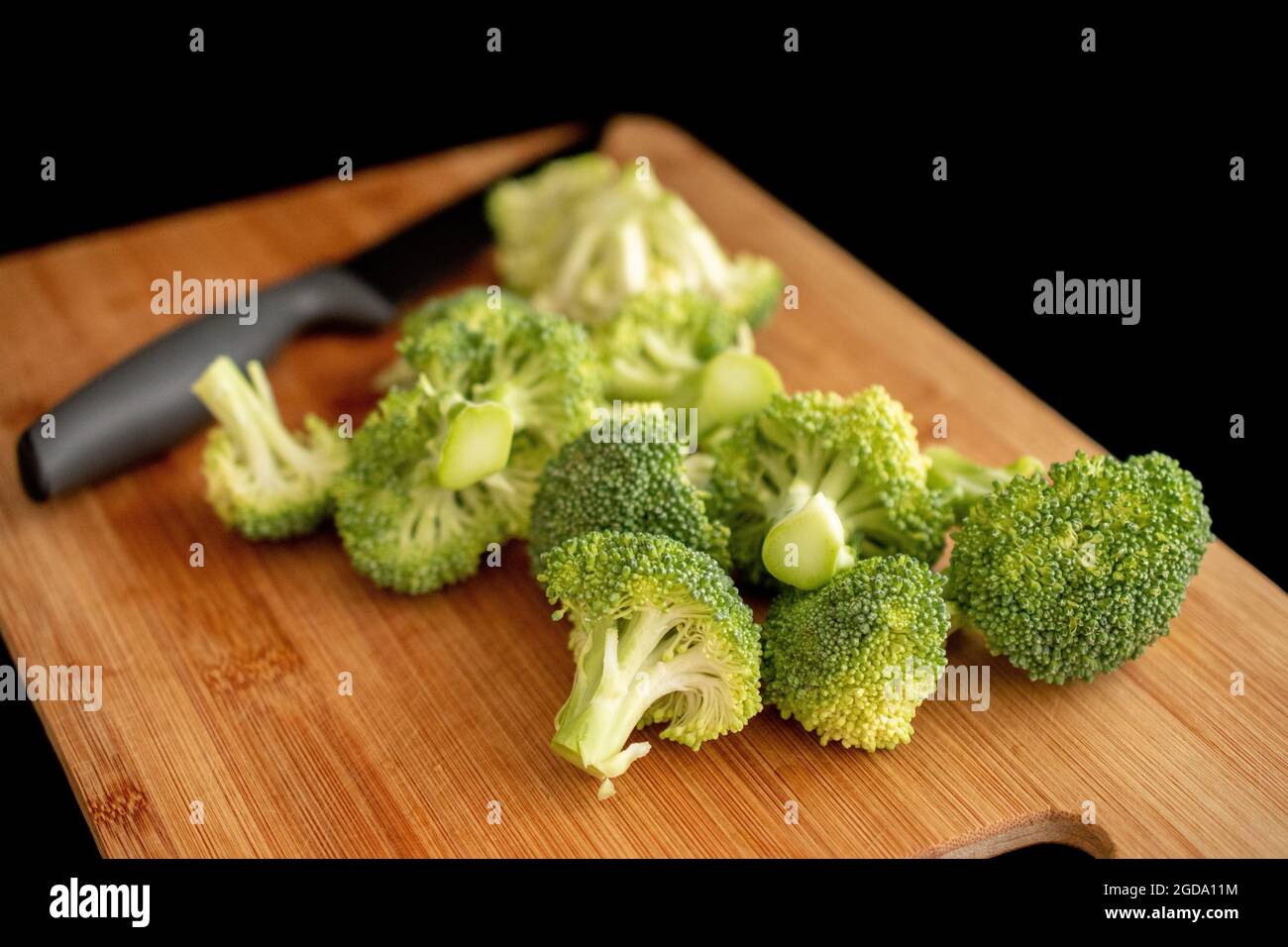 Green not cooked broccoli on a bamboo board, close-up, on a black ...