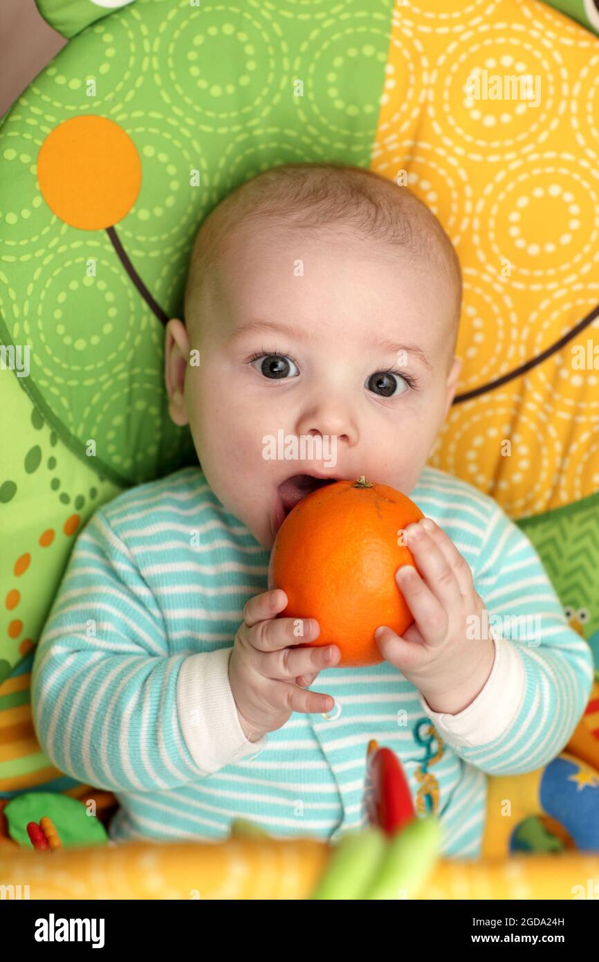 A child biting orange in seesaw at home Stock Photo - Alamy