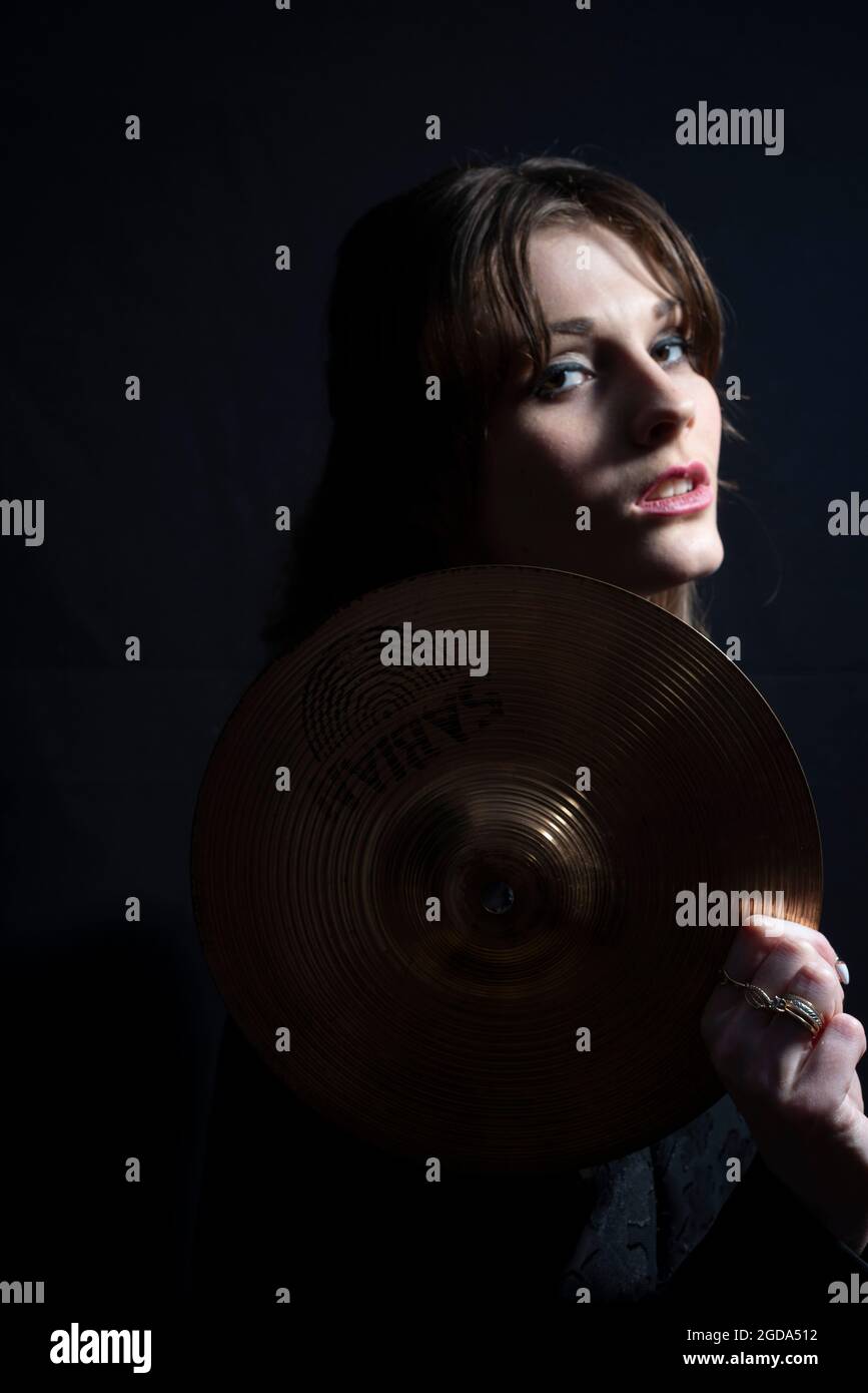 girl model musician in black, holding a snare drum cymbal, looks to the ...