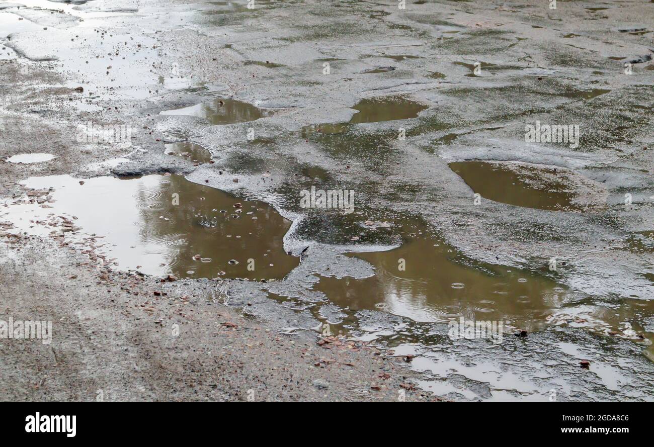 A water-filled hole in an asphalt road. A rainy day in a big city, cars ...